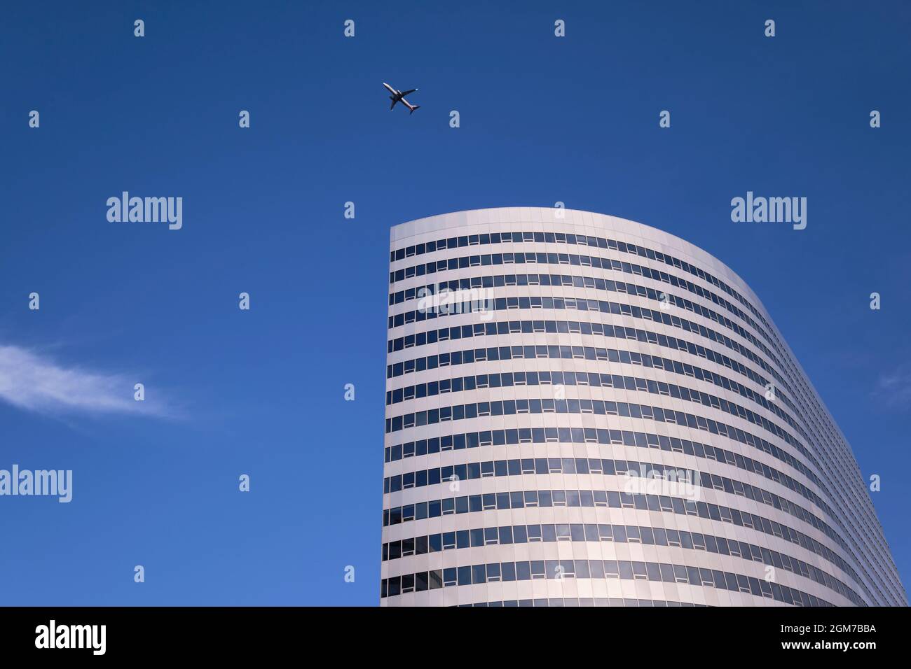 A plane from Reagan National Airport flies by a curved, modern silver ...