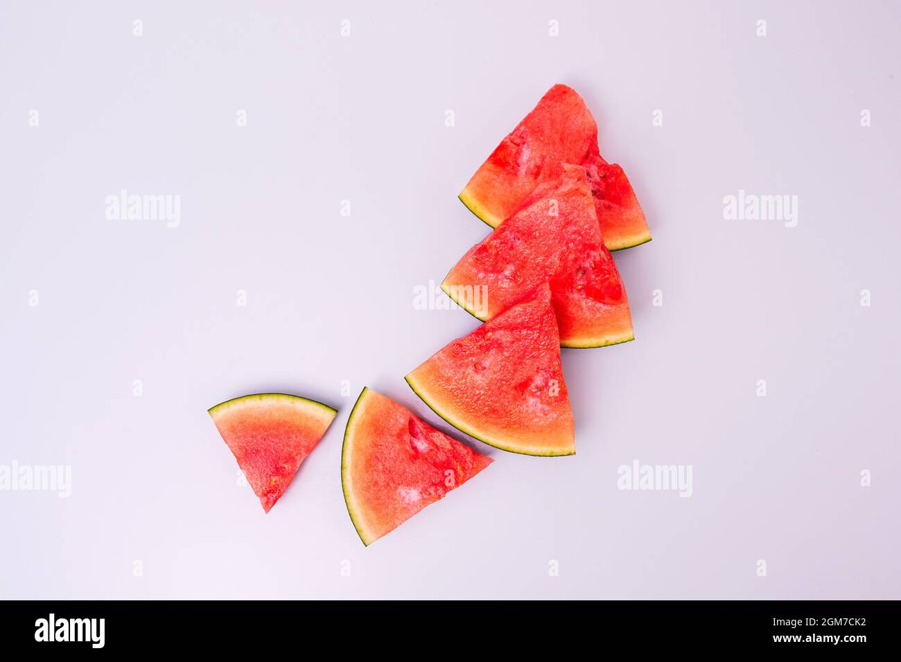 Summer watermelon chunks with seedless red meat on plain blue ...