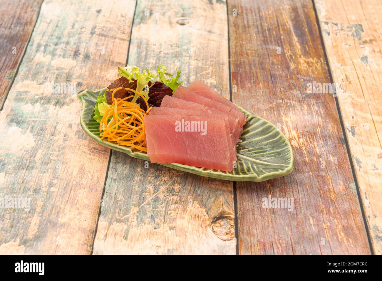 Serving of delicious Japanese red tuna sashimi sushi on green plate ...