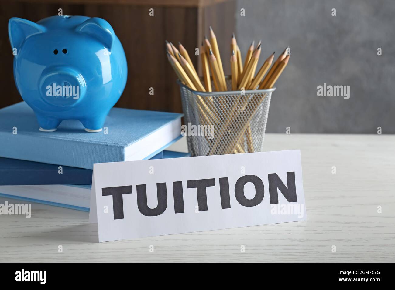 Paper with word TUITION and piggy bank on table Stock Photo - Alamy