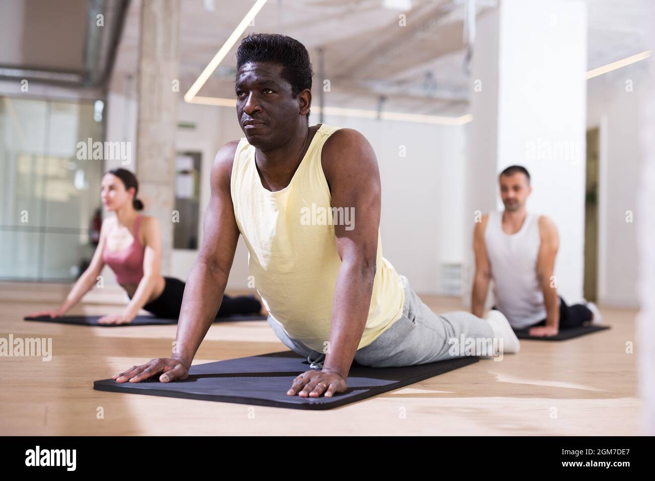 African American man doing pilates exercises with group Stock Photo - Alamy