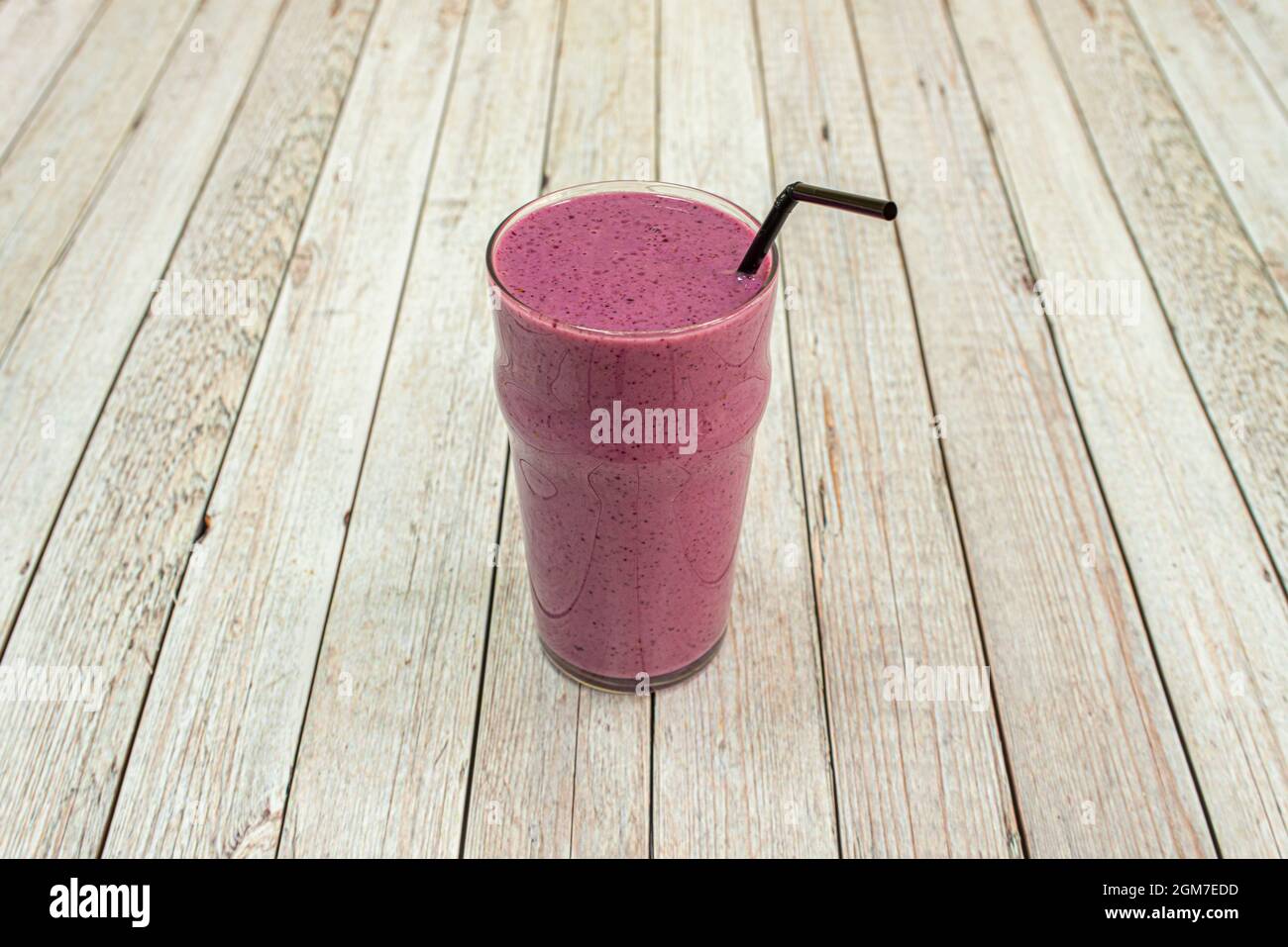 attractive red fruit juice with a straw served in a tall crystal glass ...