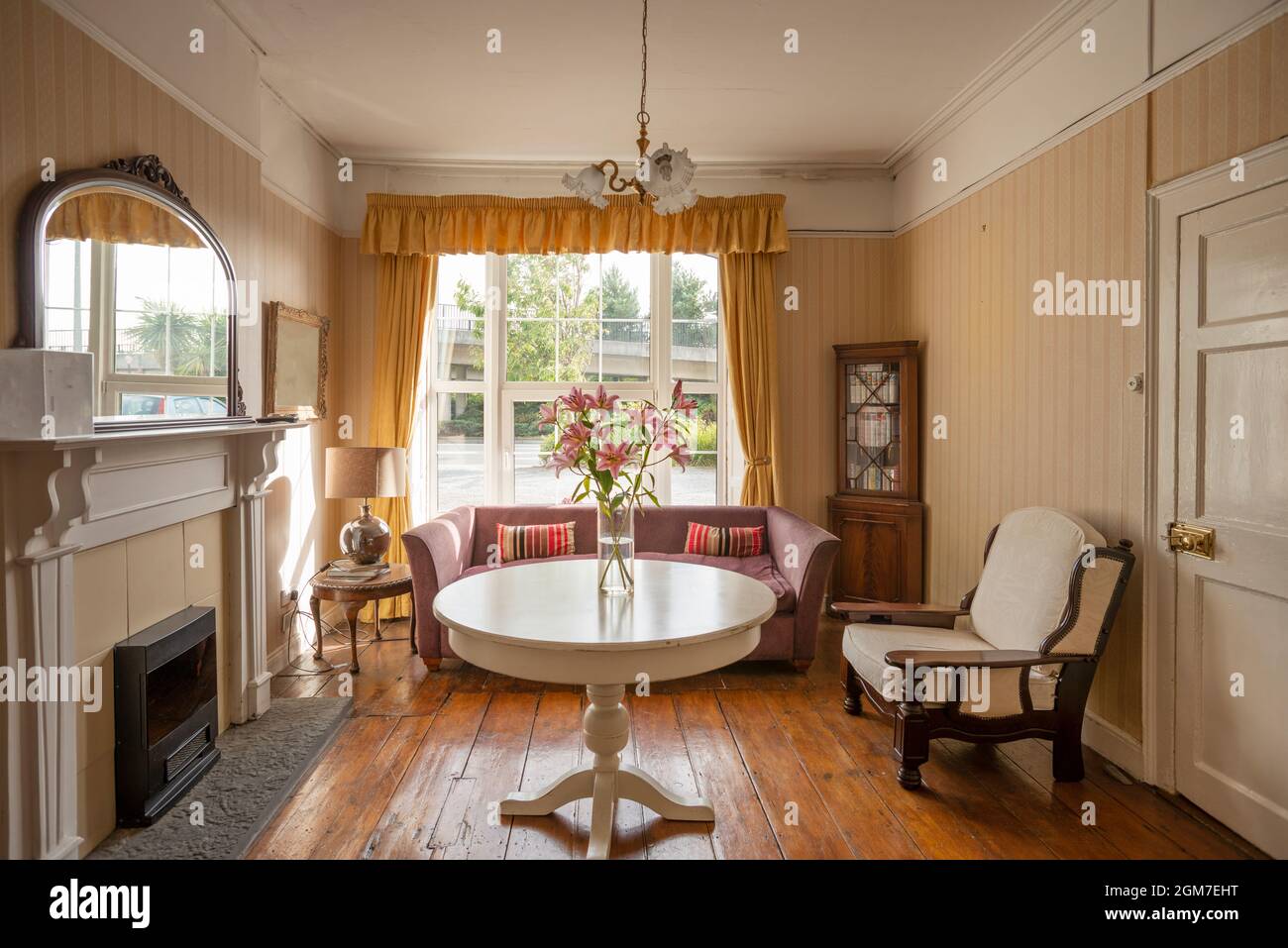 Vintage British living room with wooden floors and lilies on the table ...