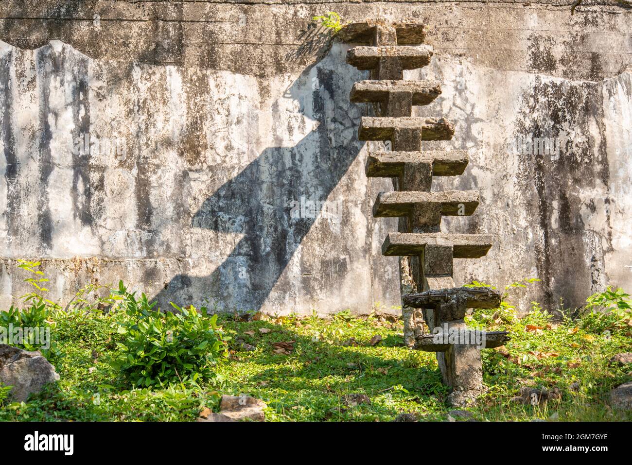 Decrepit concrete staircase attached to concrete wall and grassy floor ...