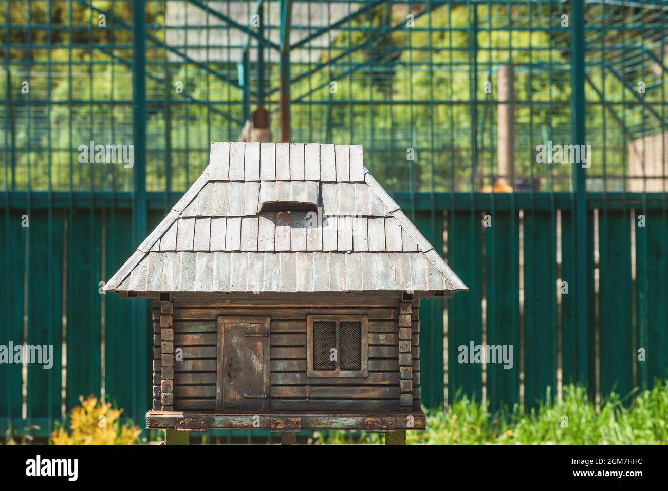 Small iron model of an old house by green fence background. Metal model ...