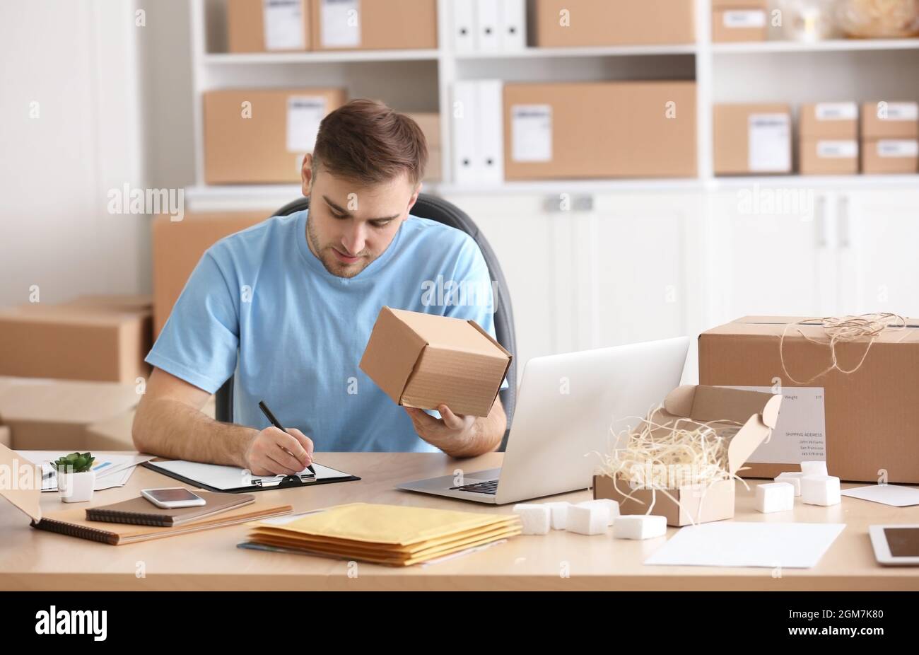 Young man preparing parcel for shipment to client in home office Stock ...