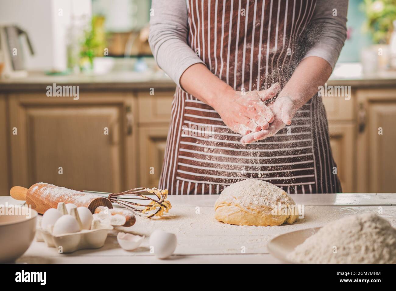 Woman slap his hands above dough closeup. Baker finishing his bakery ...
