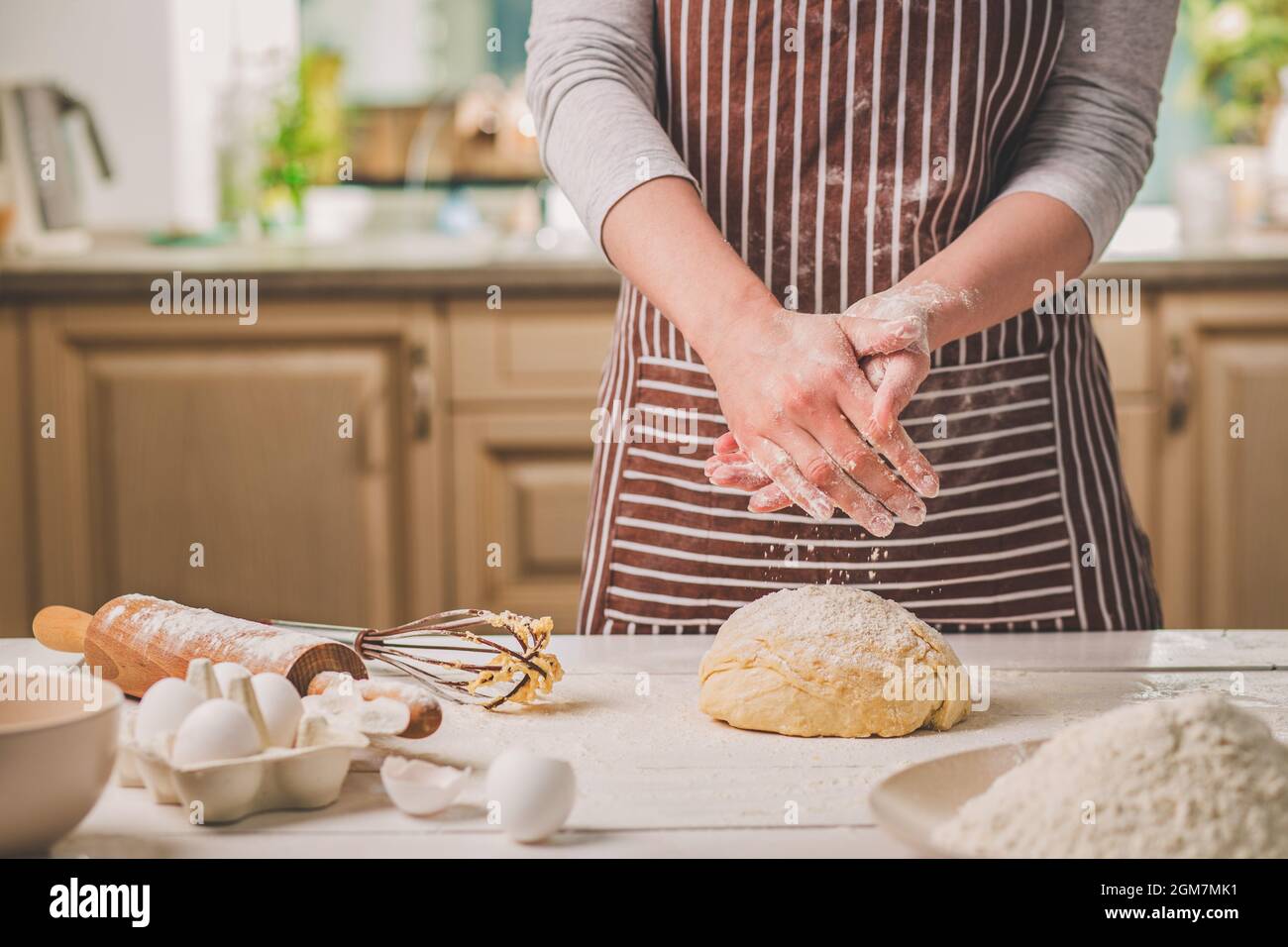 Woman slap his hands above dough closeup. Baker finishing his bakery ...