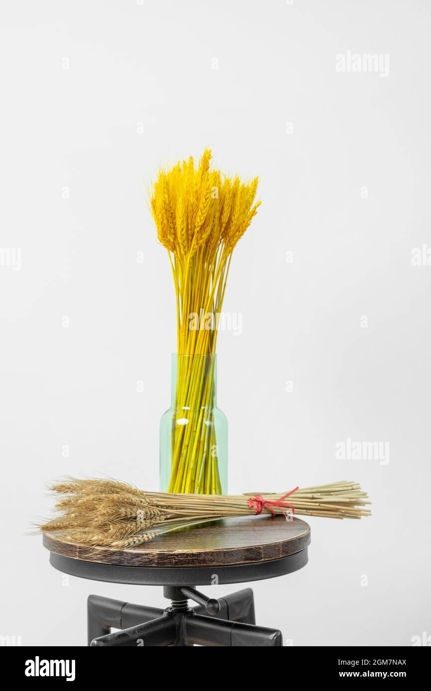 Bunch of wheat inside green glass vase and another bunch on wooden ...