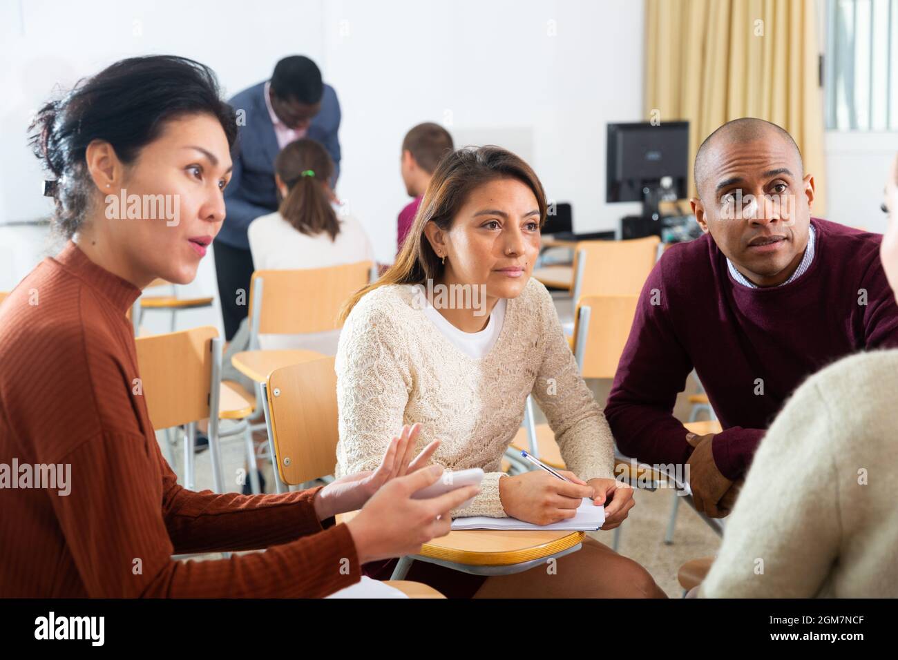 Positive students are talking about homework at desk Stock Photo - Alamy