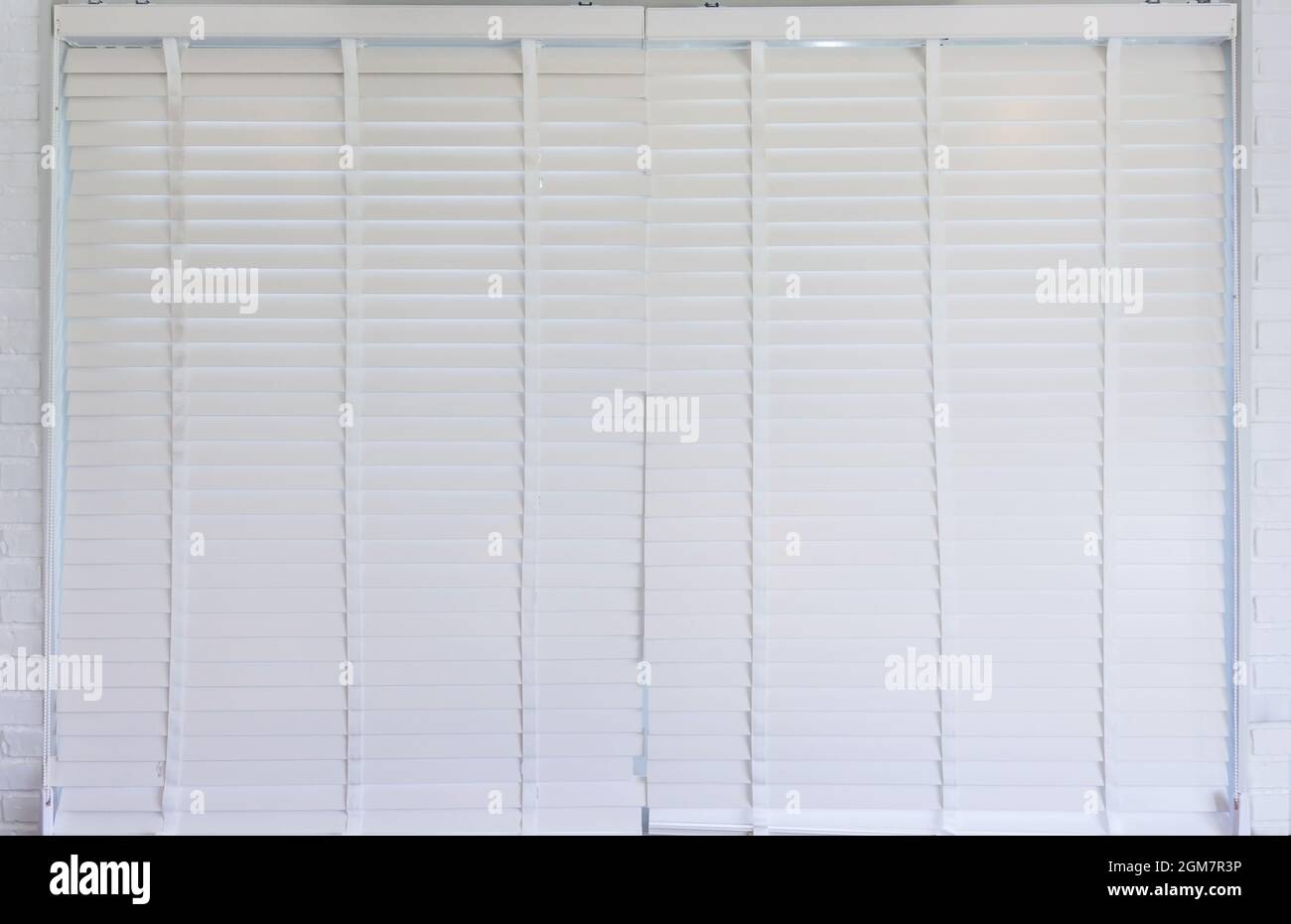 Sun-protection jalousie of white color on the window in a bright sunny ...