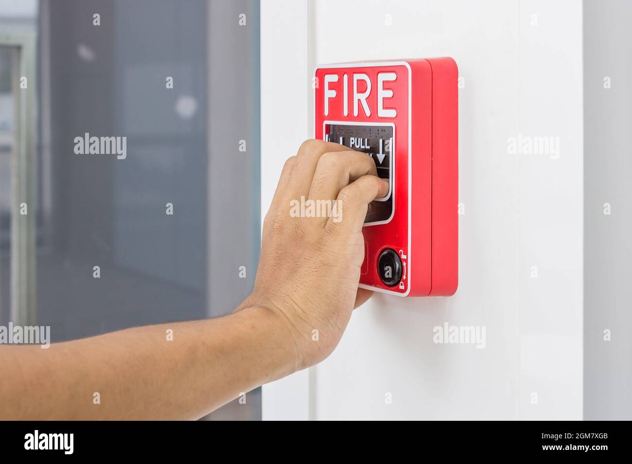 Hand of man pulling fire alarm switch on the white wall as background ...