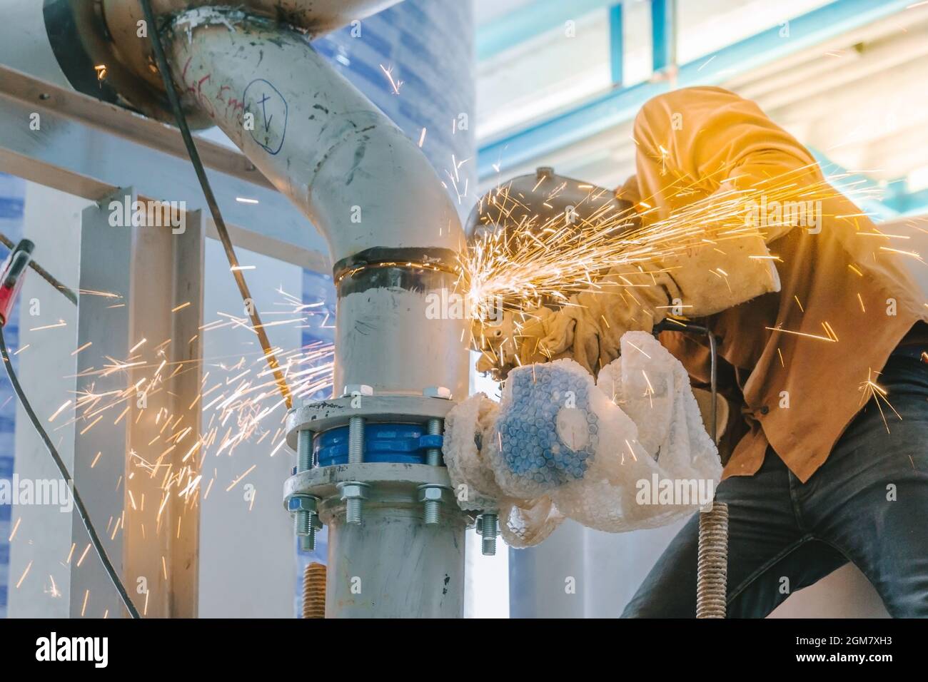 Heavy industry worker grinding steel pipe with wear protective mask by electric wheel grinding ...