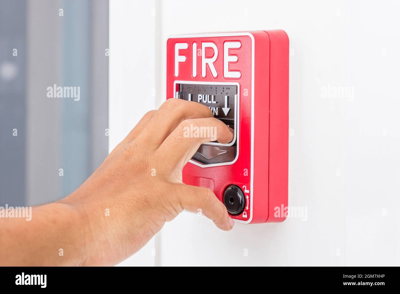 Hand of man pulling fire alarm switch on the white wall as background ...