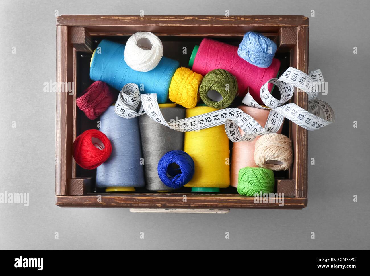 Wooden box with sewing threads and crocheting clews on grey background ...