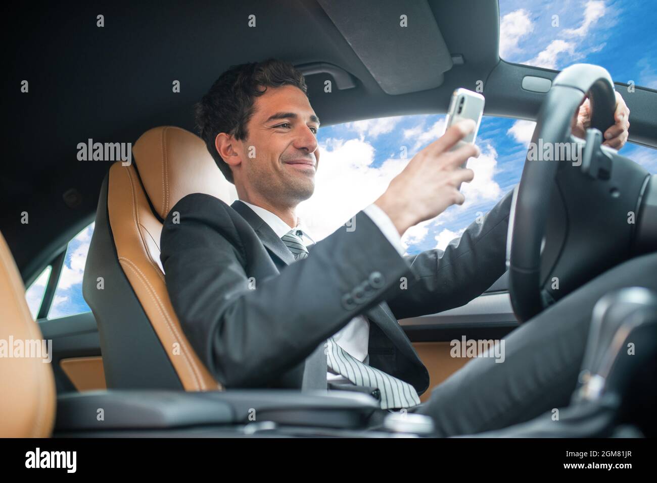 Young businessman using his mobile phone while driving, dangerous ...