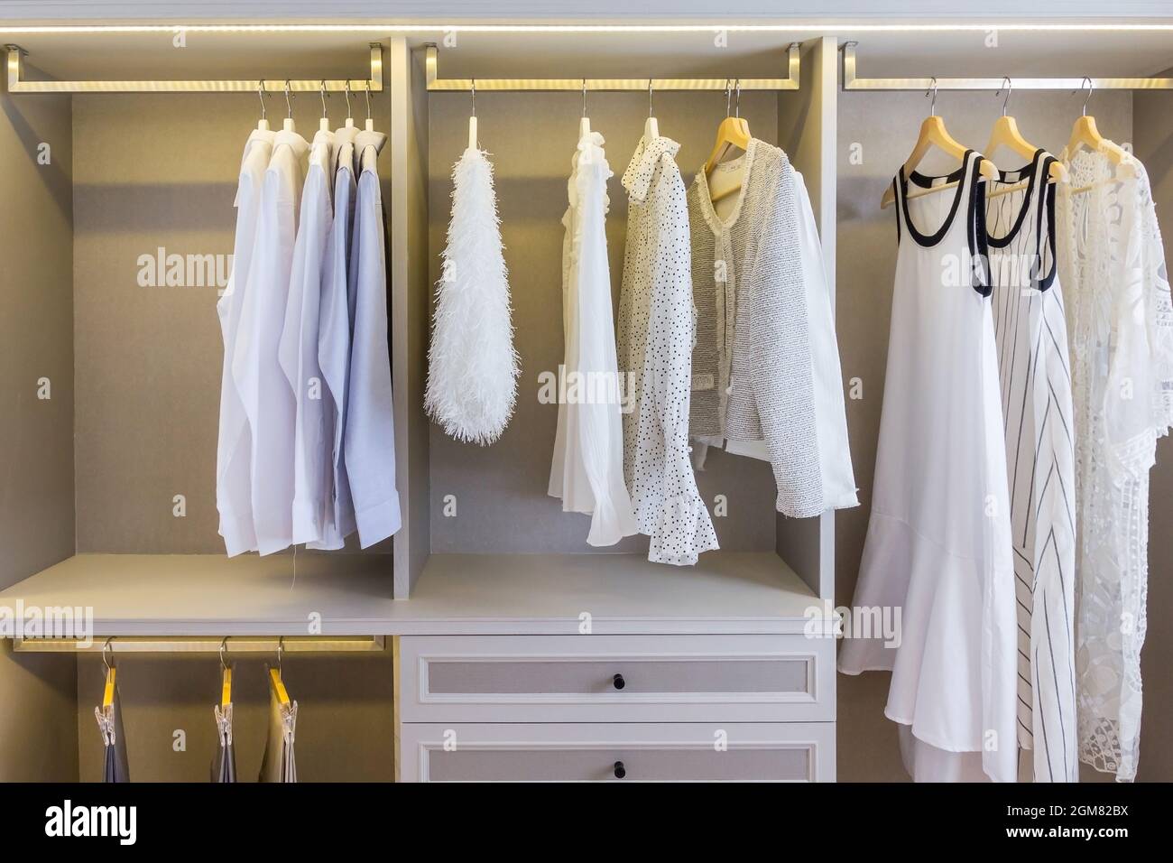 modern wooden wardrobe with clothes hanging on rail in walk in closet ...