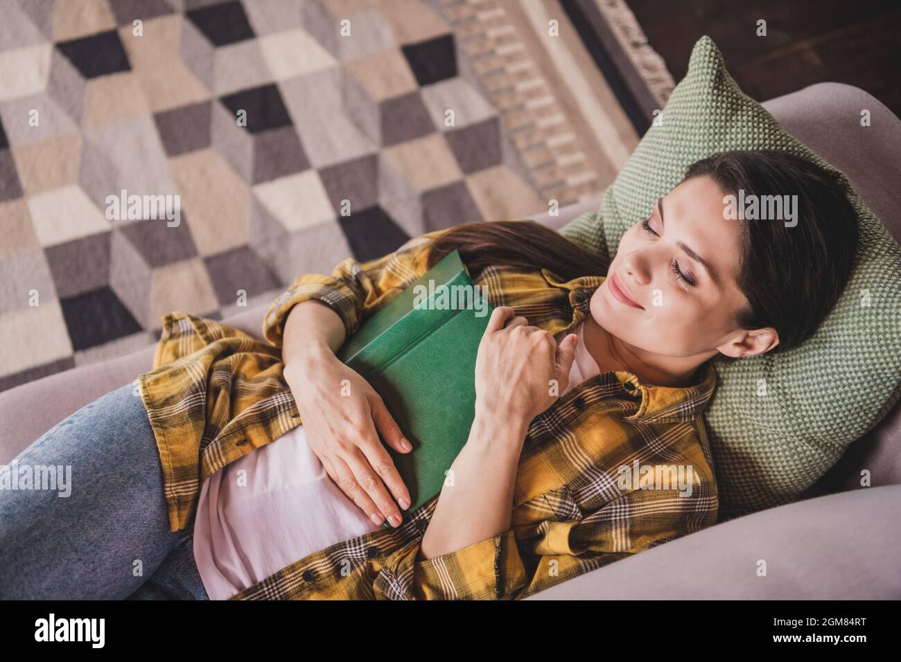 Photo of young relaxed happy positive woman lie sofa sleep hold hands ...