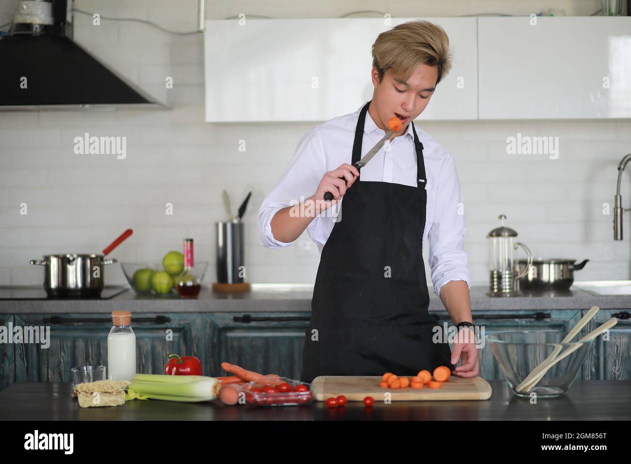 A young Asian cook in the kitchen prepares food in a cook suit Stock ...