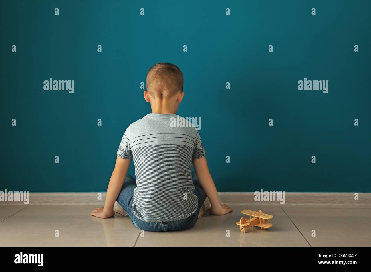 Little boy sitting near dark wall in empty room. Autism concept Stock ...