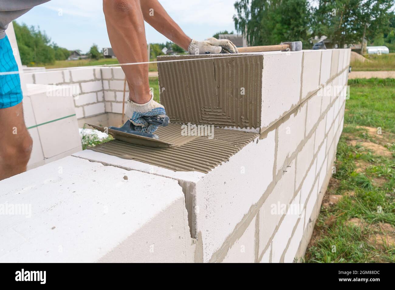 Builder uses a notched trowel to apply the cement mixture to the ...