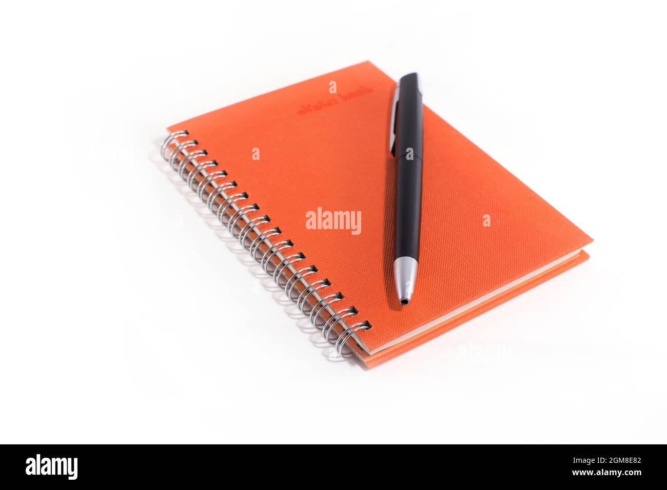 Orange notebook with black pen on white background Stock Photo - Alamy