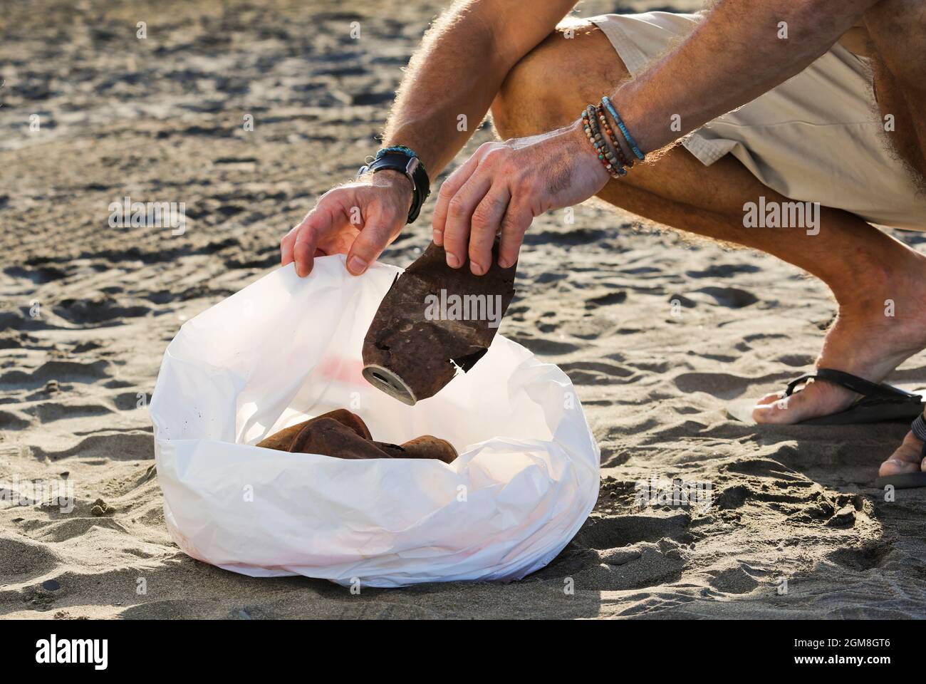 Clean the beach from trash. Man hand picking up empty trash from soda ...