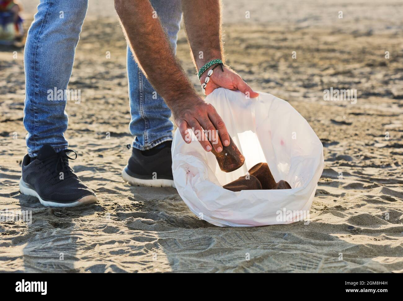 Clean the beach from trash. Man hand picking up empty trash from soda ...