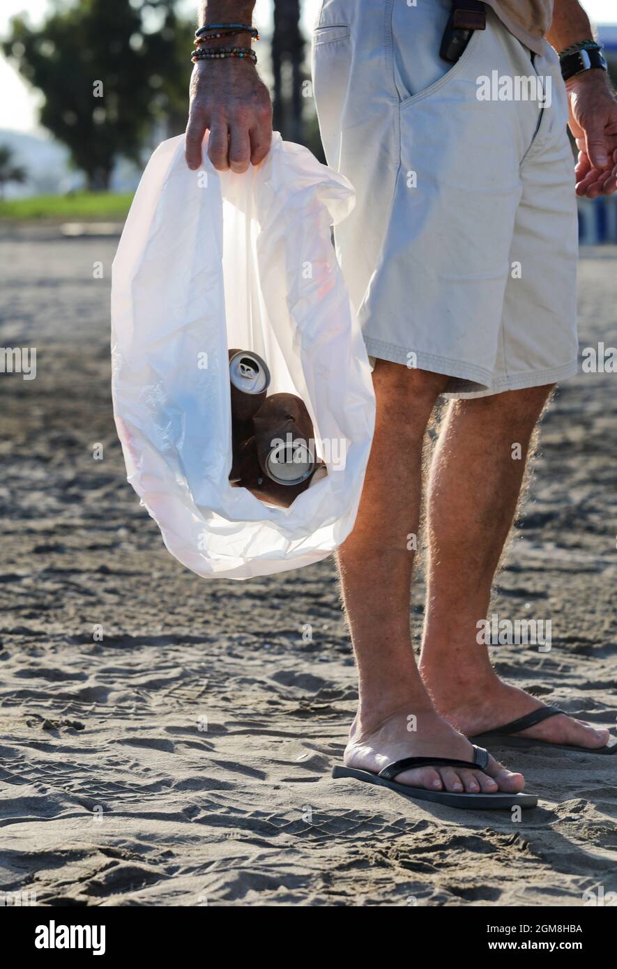 Clean the beach from trash. Man hand picking up empty trash from soda ...
