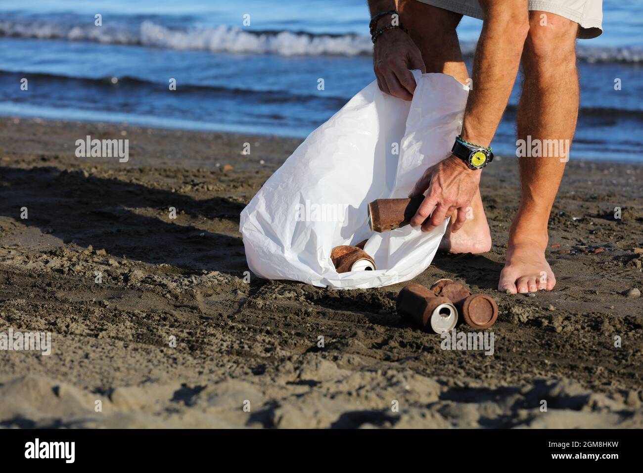 Clean the beach from trash. Man hand picking up empty trash from soda ...