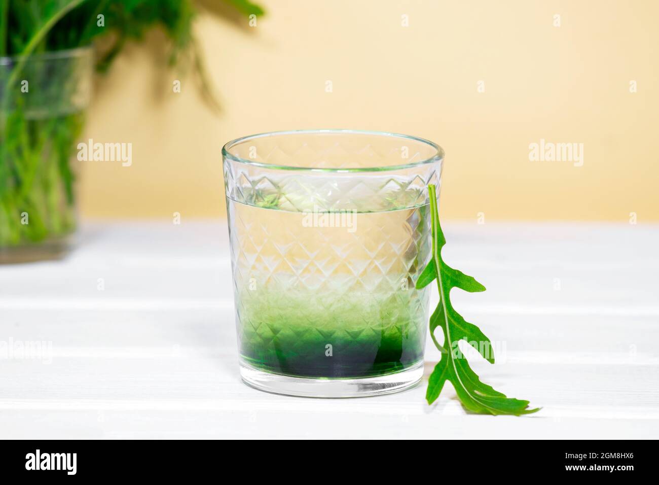 Green Chlorophyll or Chlorella drink in glass with water on white table ...