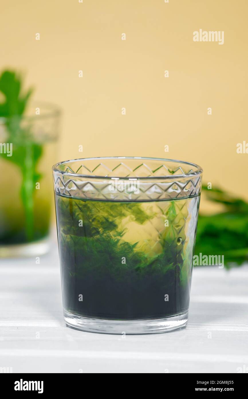 Green Chlorophyll or Chlorella drink in glass with water on white table ...