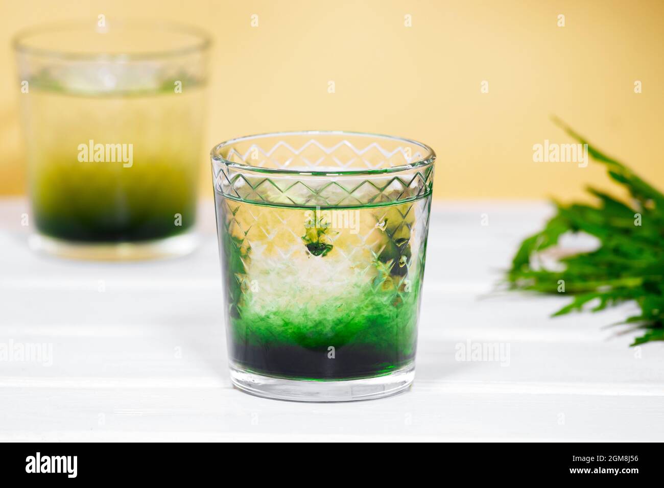 Green Chlorophyll or Chlorella drink in glass with water on white table ...