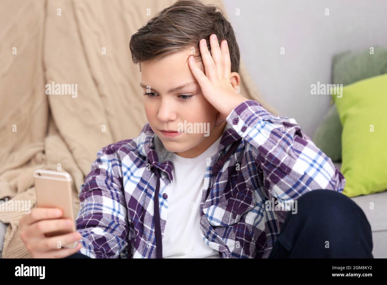 Upset teenage boy with smartphone indoors Stock Photo - Alamy