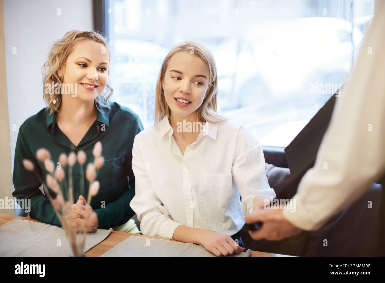 Waiter giving menu to customers in cafe Stock Photo - Alamy