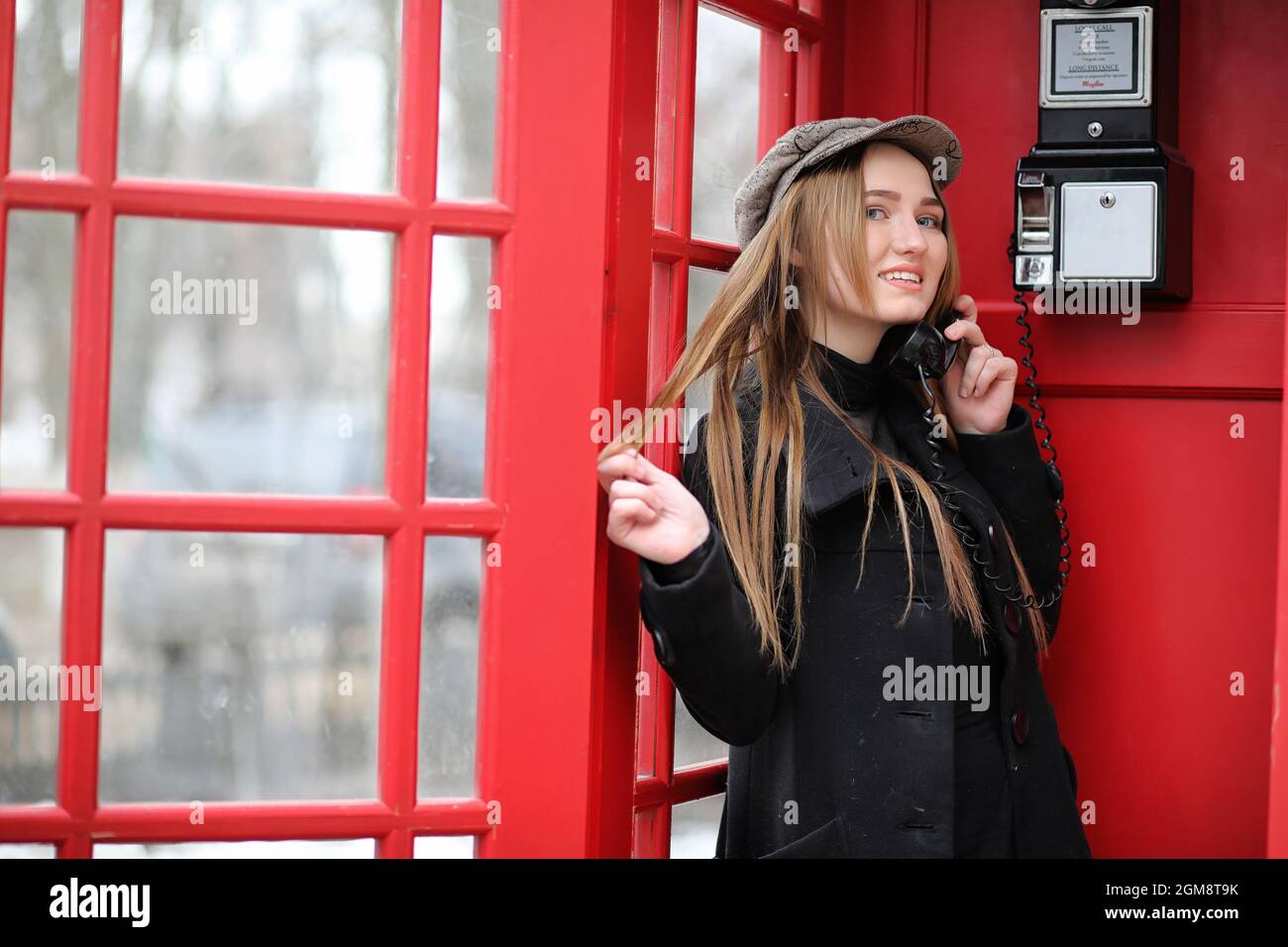 Beautiful young girl in a phone booth. The girl is talking on the phone ...