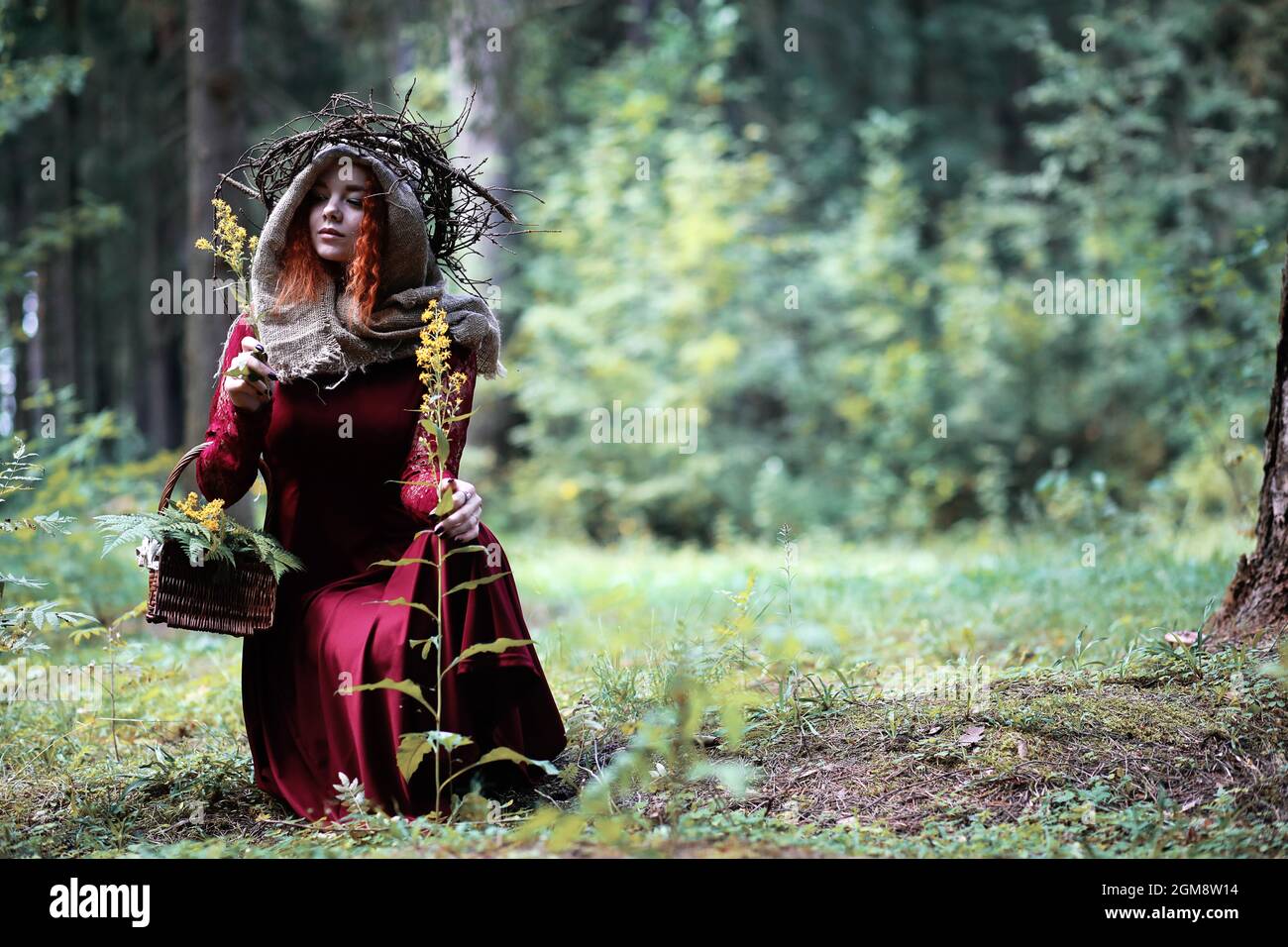 The red-haired witch holds a ritual with a crystal ball in the forest ...