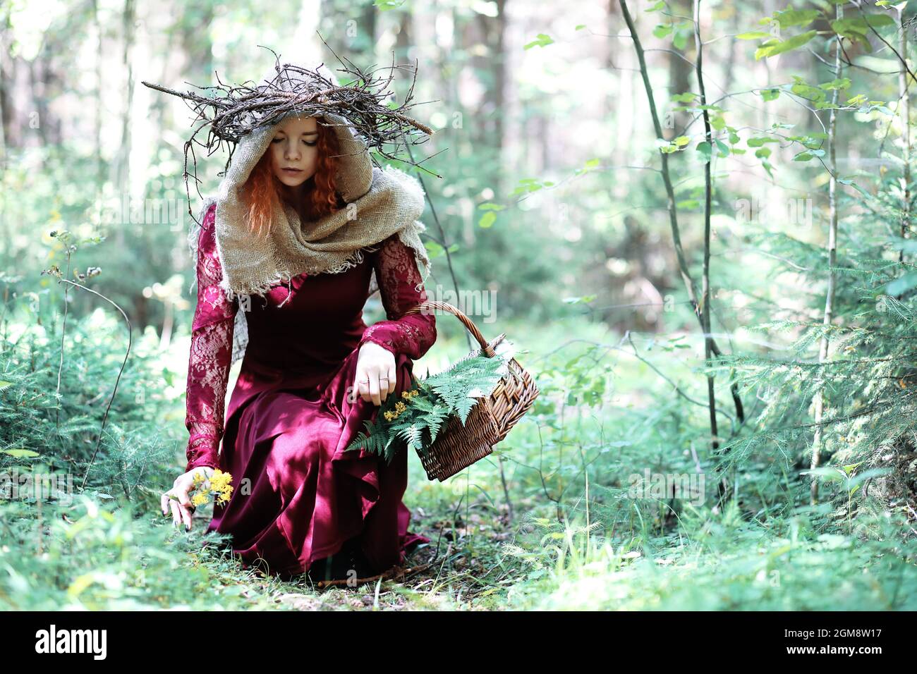 The red-haired witch holds a ritual with a crystal ball in the forest ...