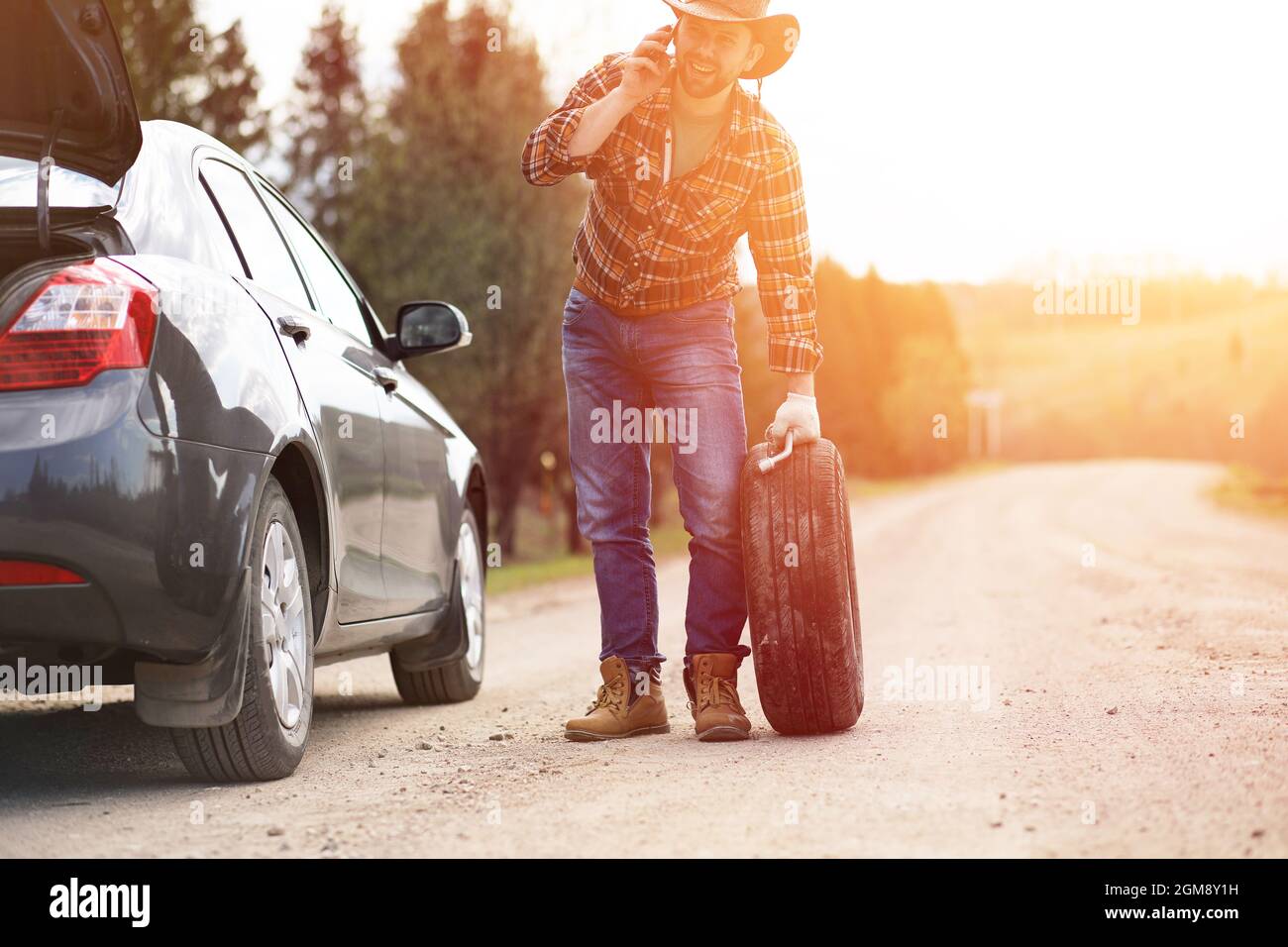The man is sitting on the road by the car in the nature Stock Photo - Alamy