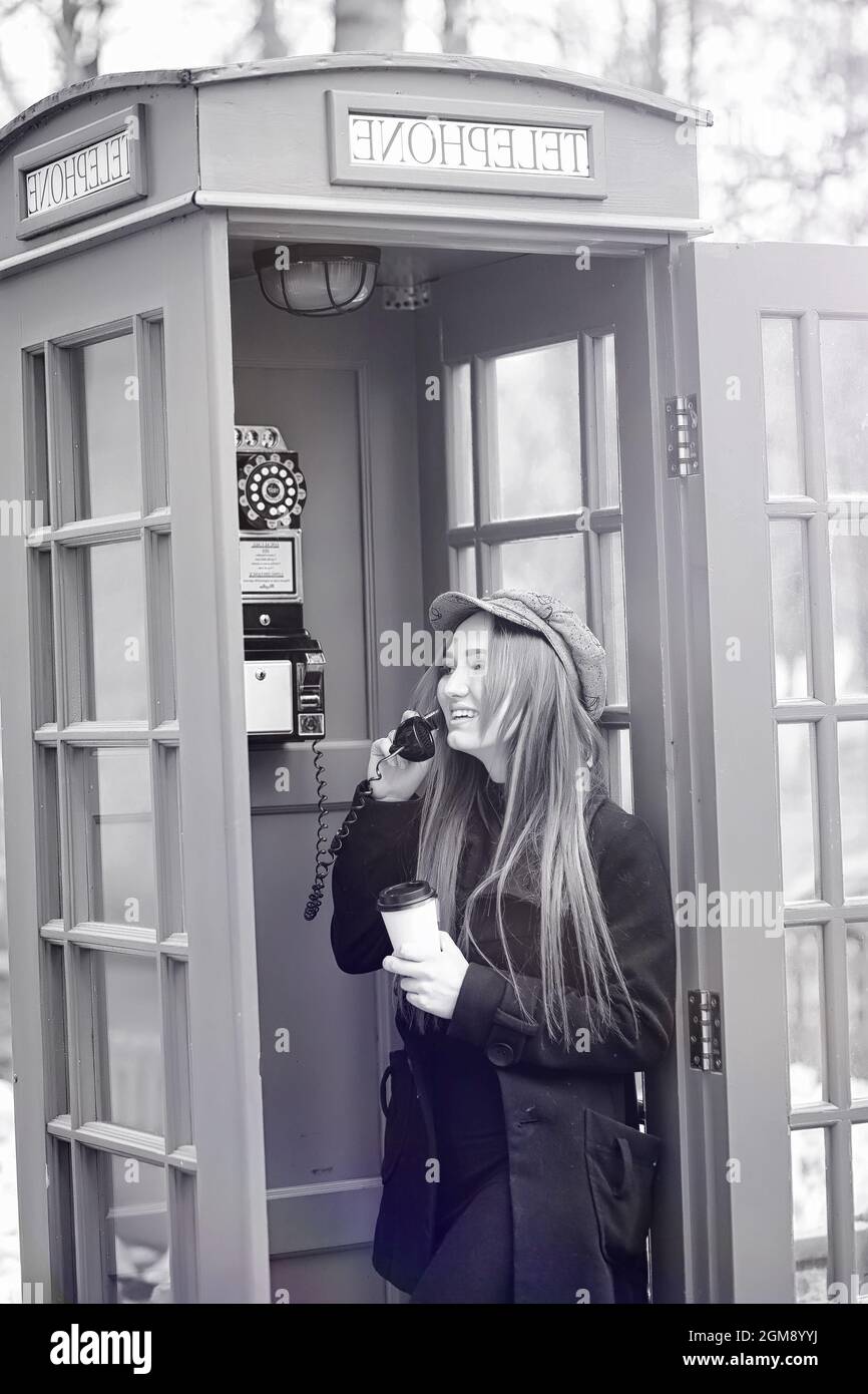 Beautiful young girl in a phone booth. The girl is talking on the phone ...