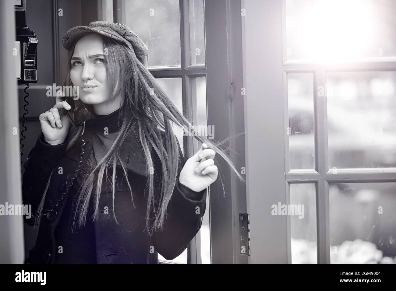 Beautiful young girl in a phone booth. The girl is talking on the phone ...