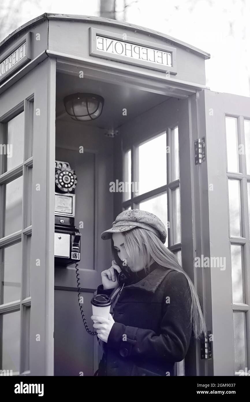 Beautiful young girl in a phone booth. The girl is talking on the phone ...