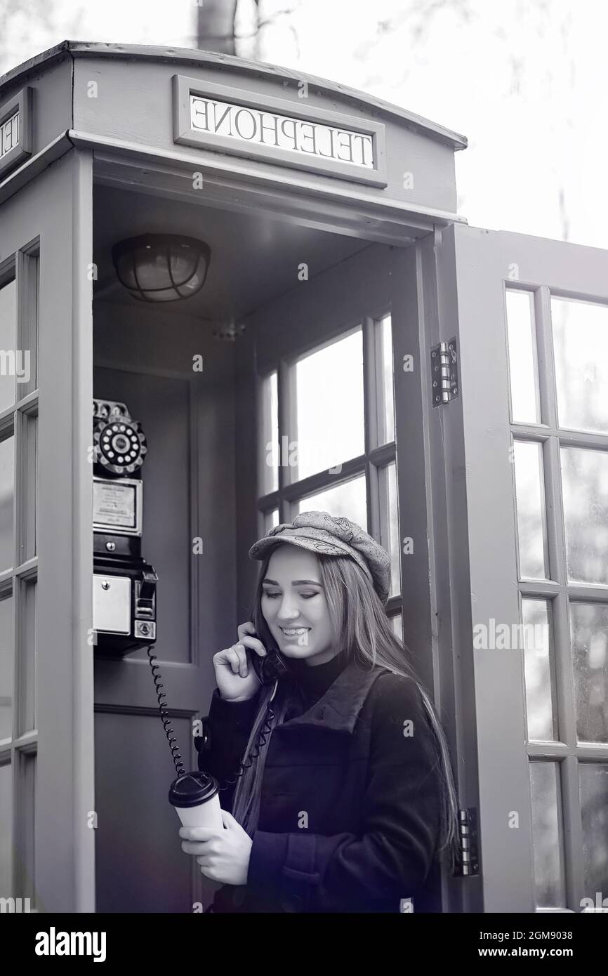 Beautiful young girl in a phone booth. The girl is talking on the phone ...