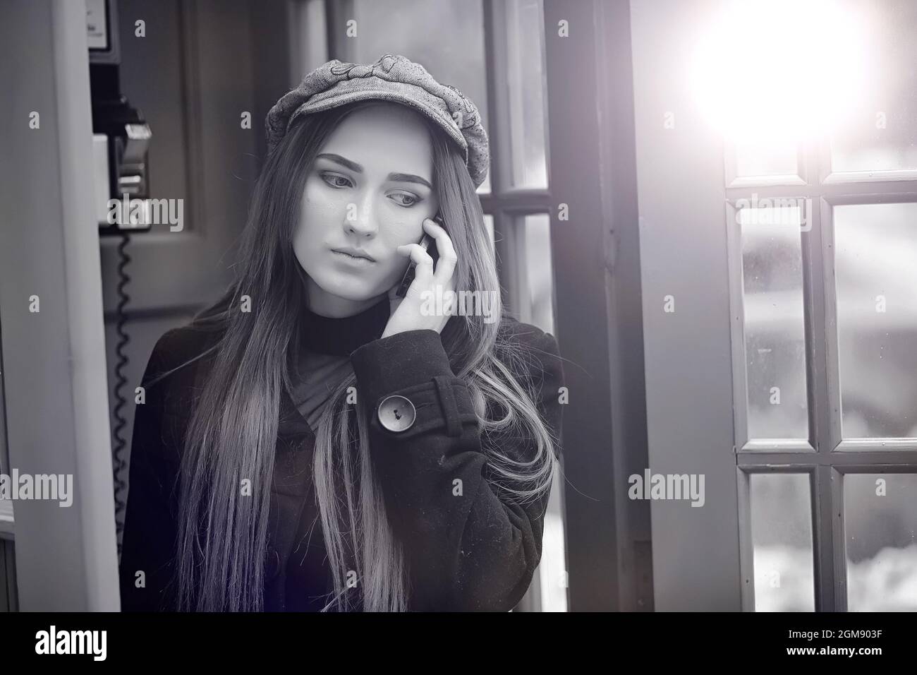 Beautiful young girl in a phone booth. The girl is talking on the phone ...