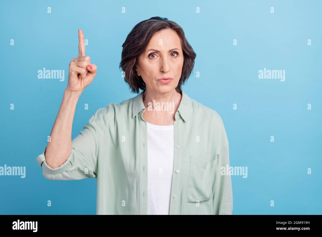 Photo portrait senior woman serious pointing finger up recommending ...