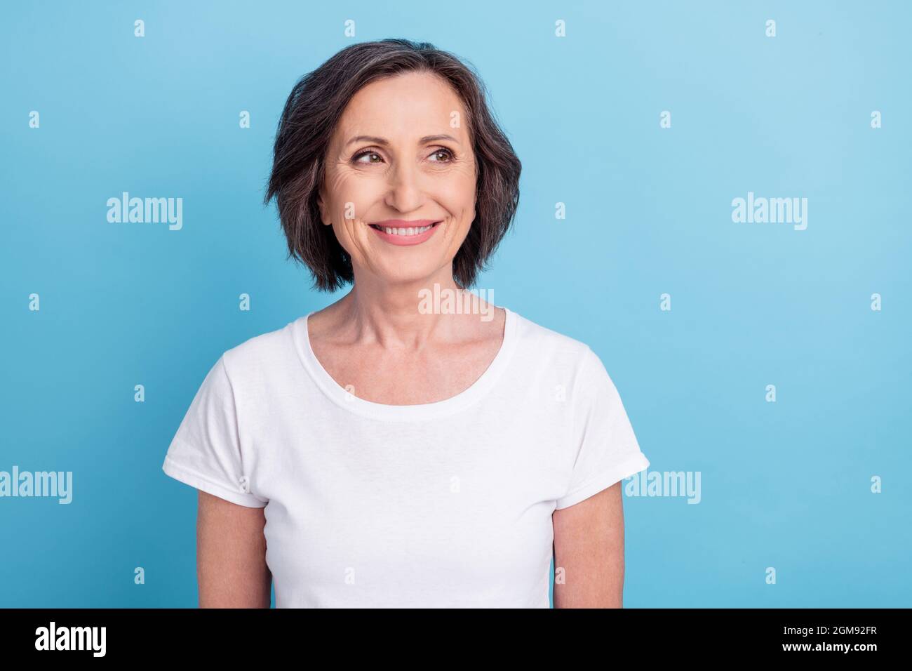 Photo portrait senior woman smiling looking blank space in white t ...