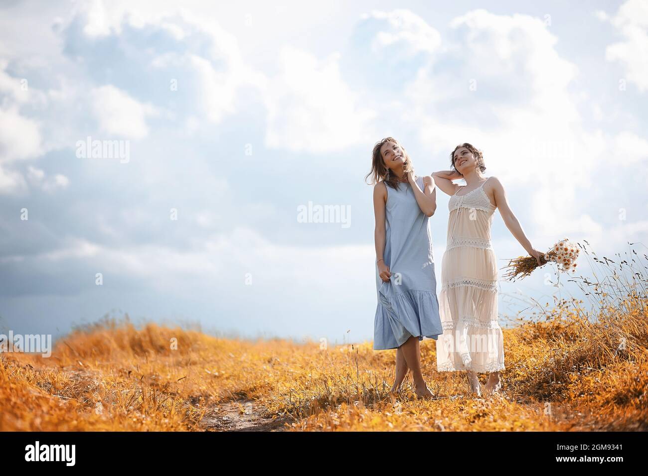 Two beautiful girls in dresses in autumn field have fun Stock Photo - Alamy