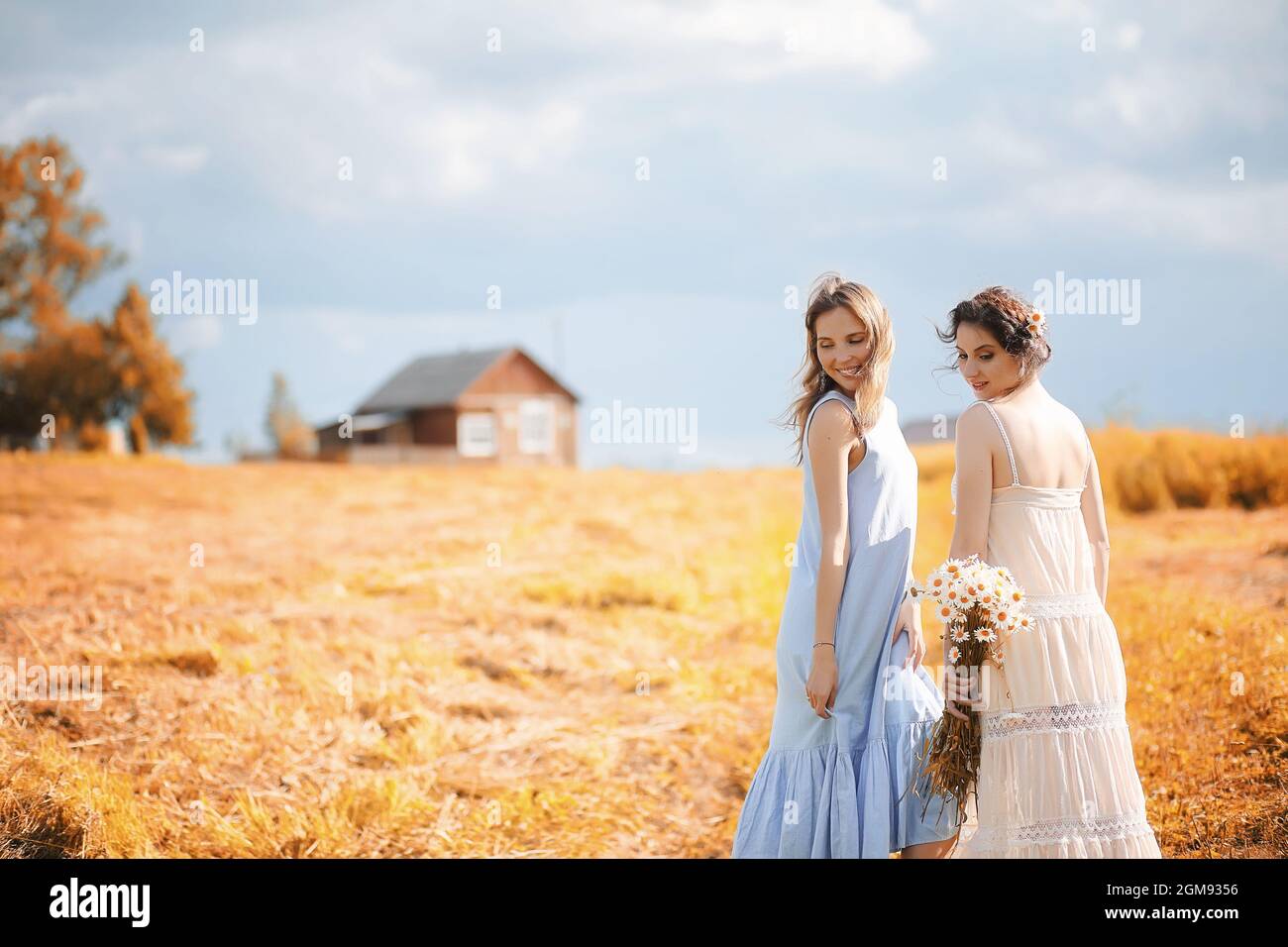 Two beautiful girls in dresses in autumn field have fun Stock Photo - Alamy