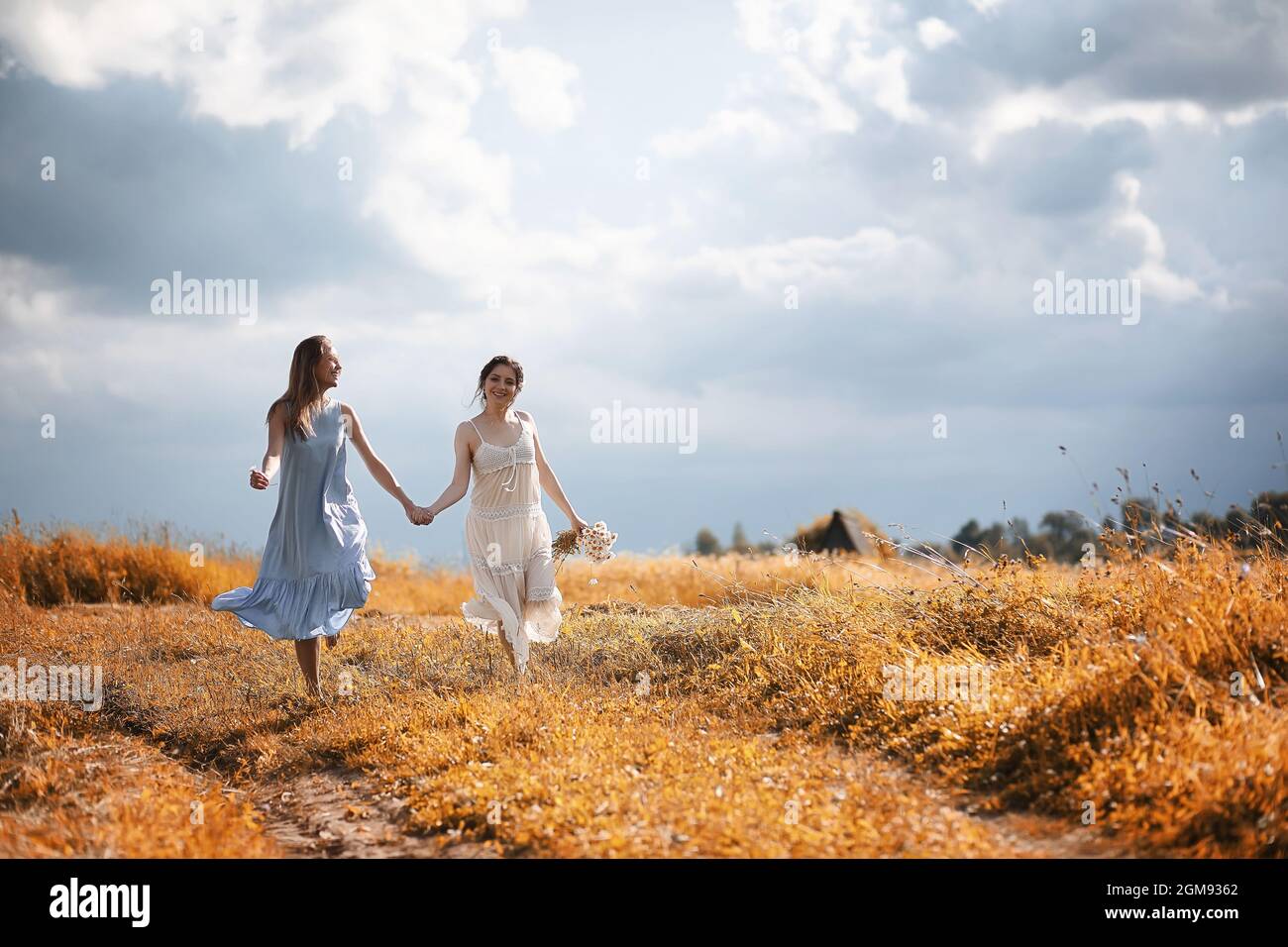 Two beautiful girls in dresses in autumn field have fun Stock Photo - Alamy