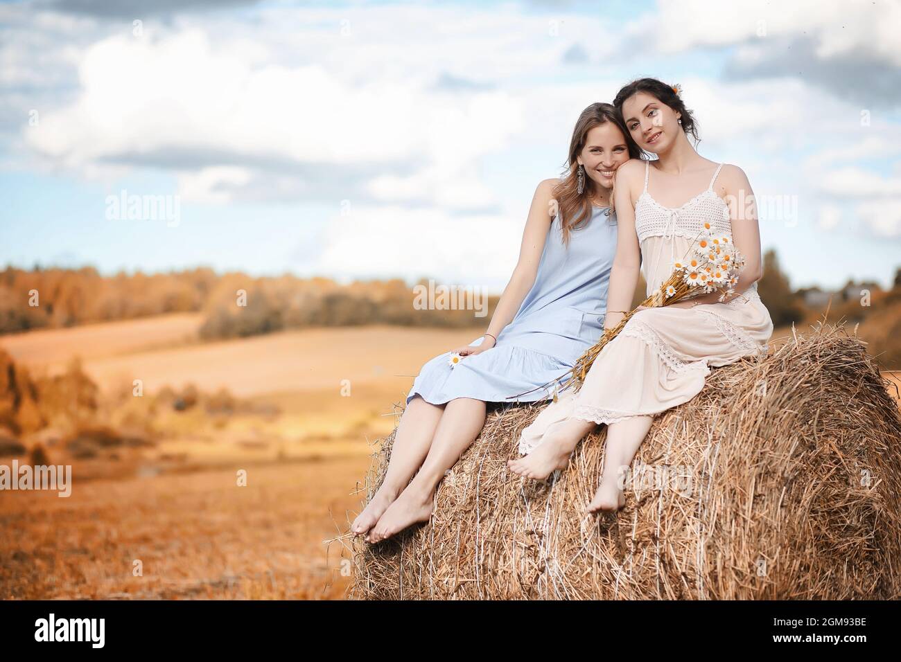 Two beautiful girls in dresses in autumn field have fun Stock Photo - Alamy